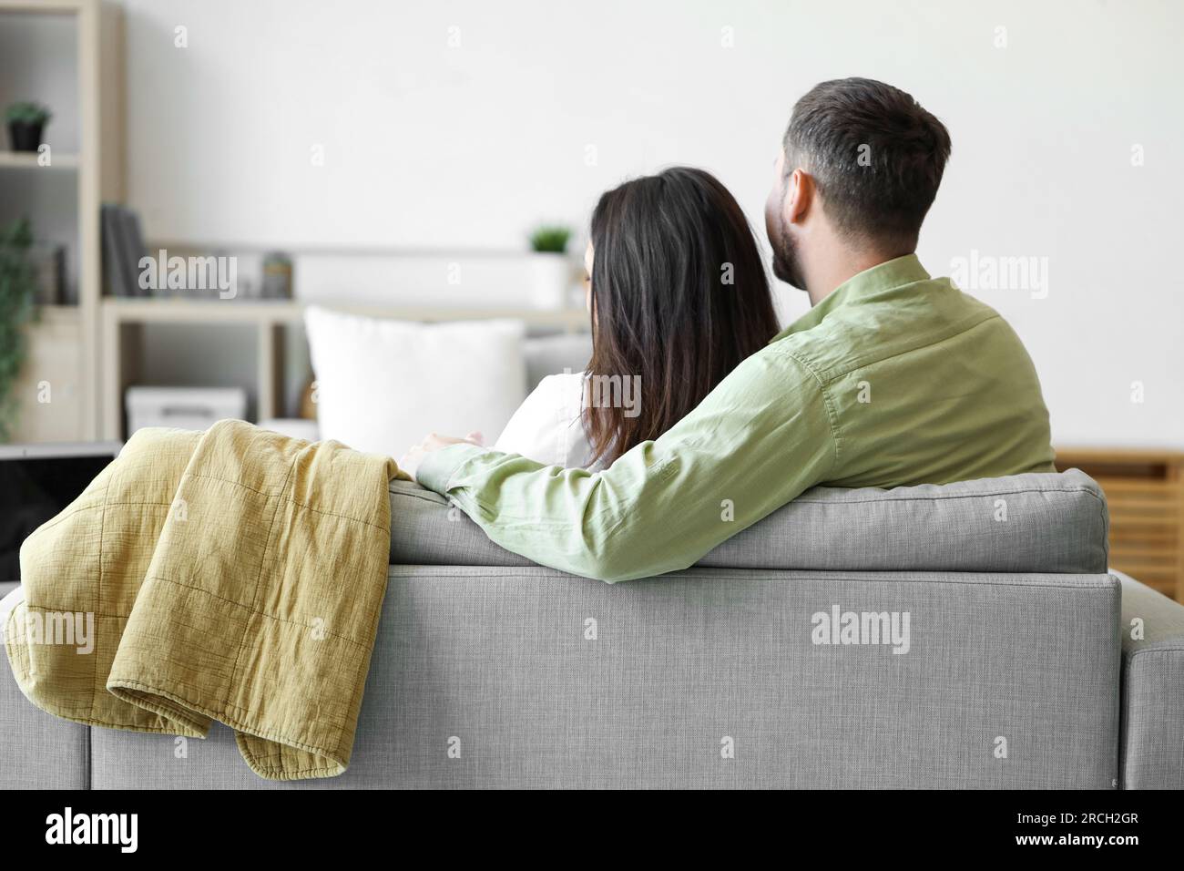 Happy young couple resting on sofa at home, back view Stock Photo - Alamy