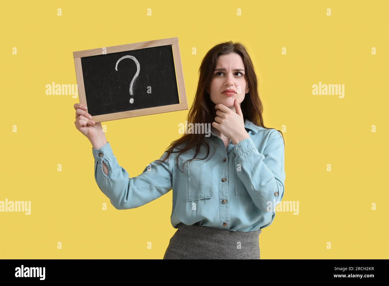 Thoughtful female teacher holding chalkboard with question mark on ...
