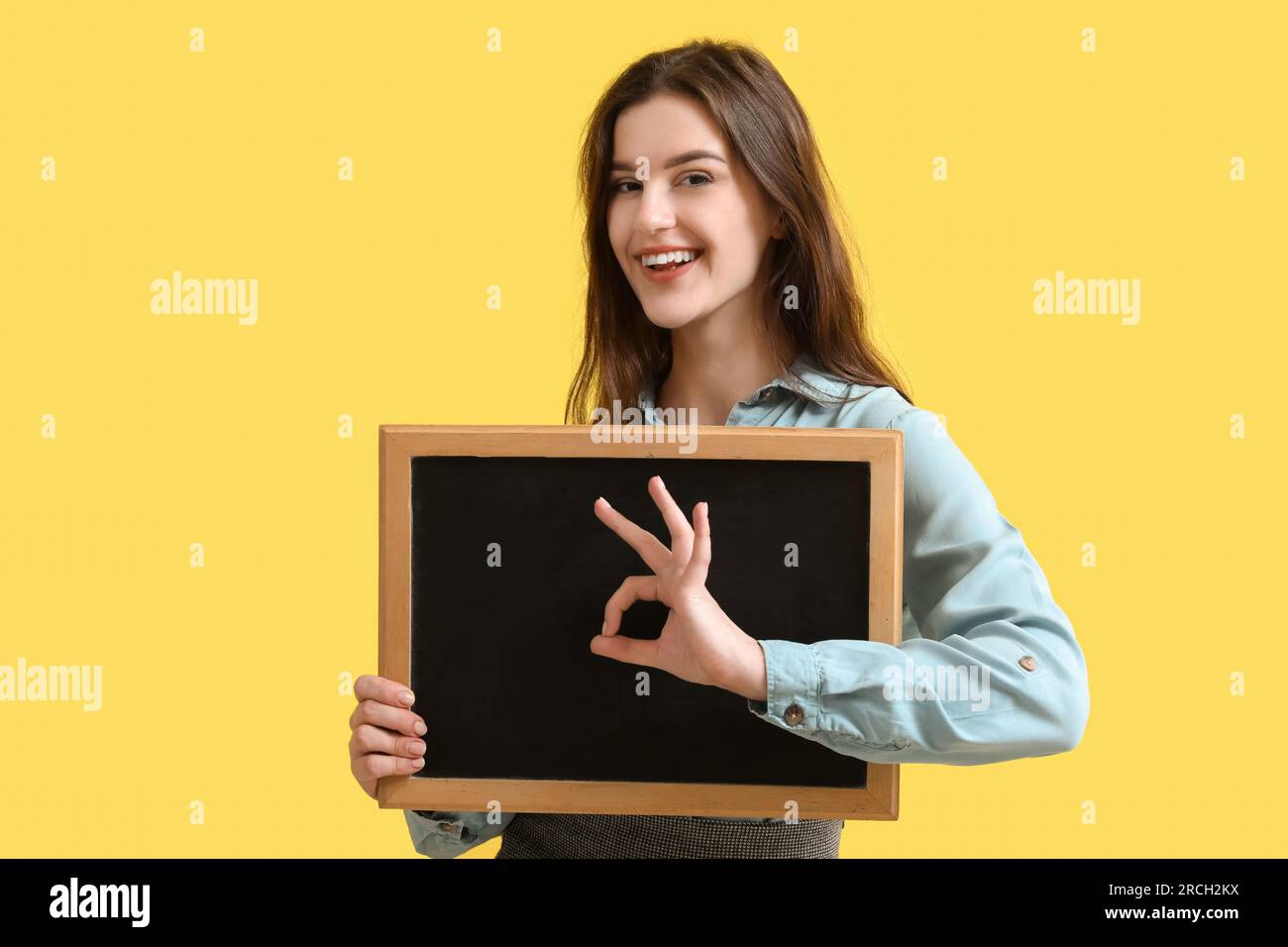 Female teacher with chalkboard showing OK on yellow background Stock ...