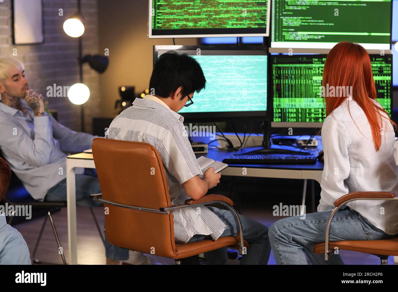 Team of young programmers working in office at night, back view Stock ...