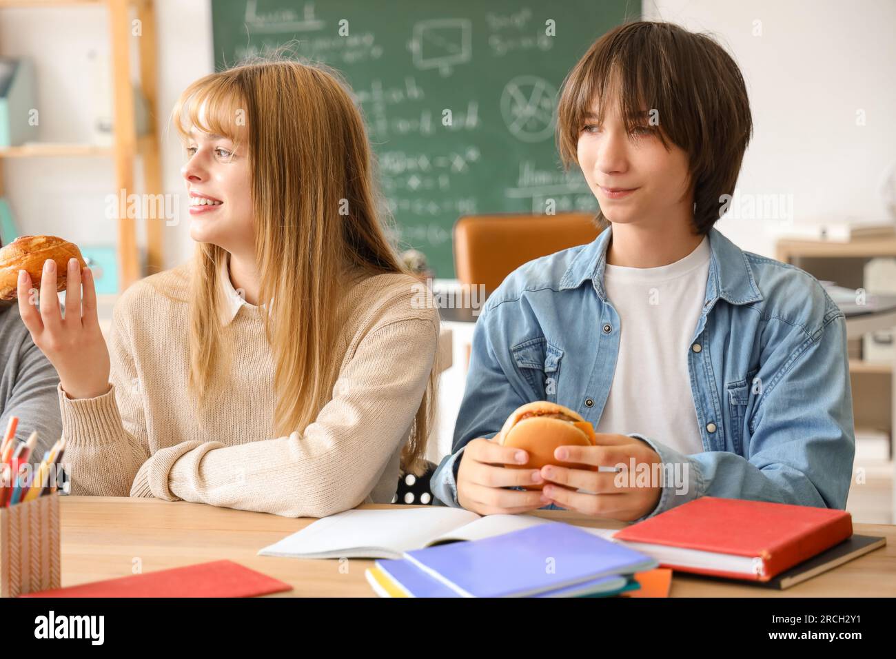 Teenage students having snacks at table in classroom Stock Photo - Alamy