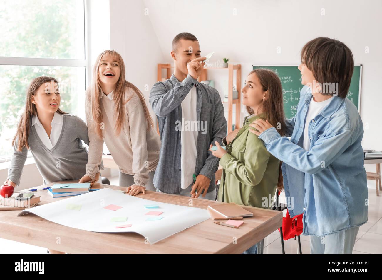 Group of teenage students performing task at table in classroom Stock ...