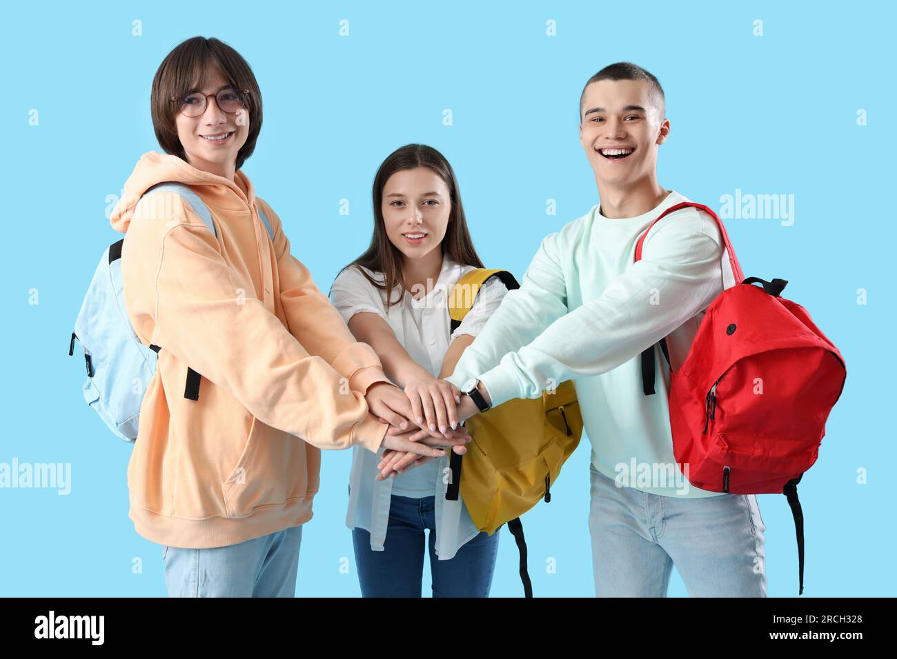 Teenage students putting hands together on blue background Stock Photo ...