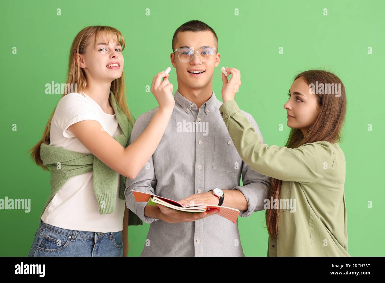 Female students with chalk pieces and their classmate on green ...