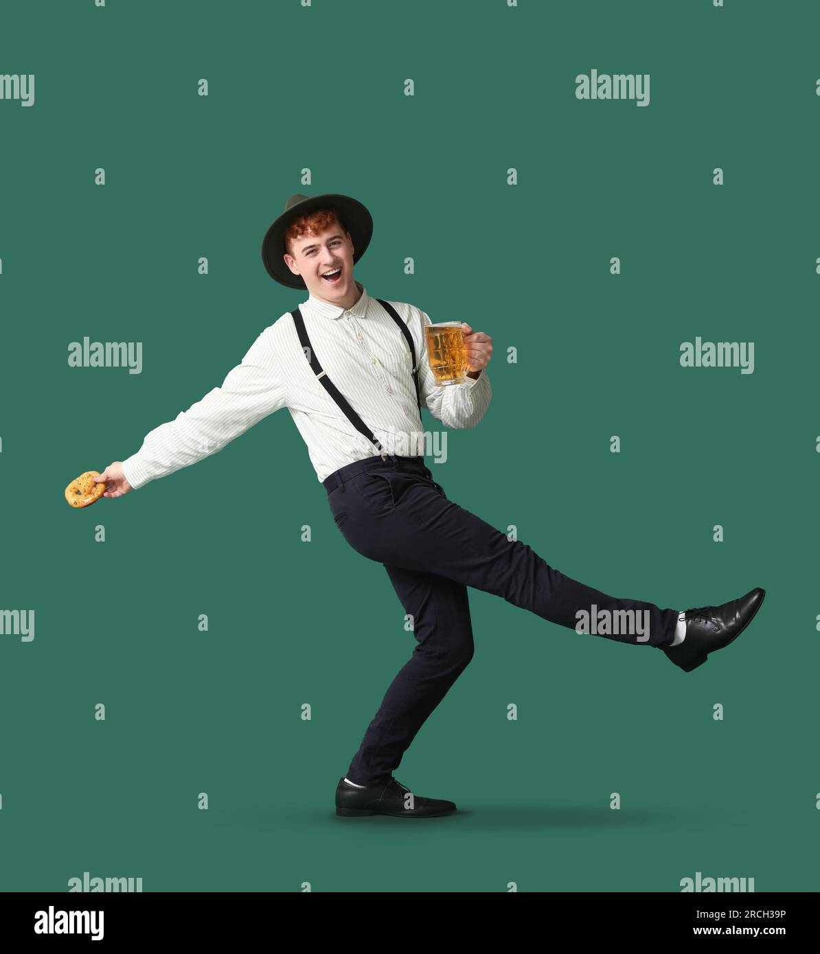 Young man in traditional German clothes with beer and pretzel dancing ...