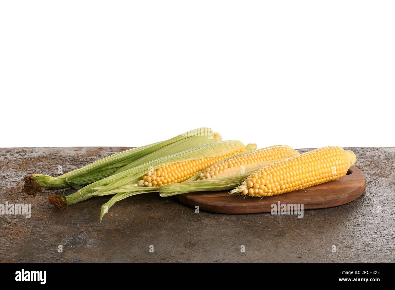Wooden board with fresh corn cobs on grunge table against white ...