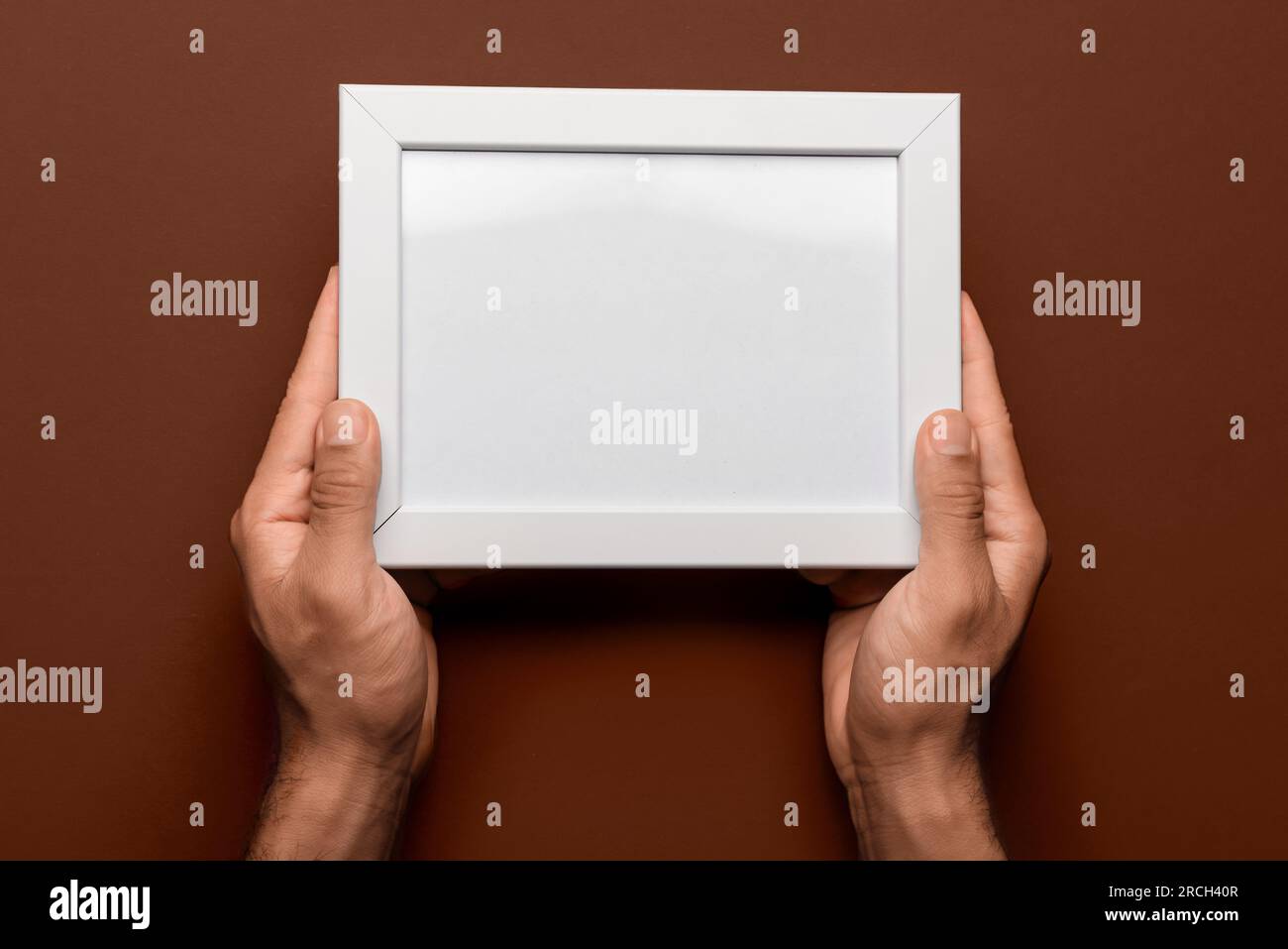 Man holding blank photo frame on brown background Stock Photo - Alamy