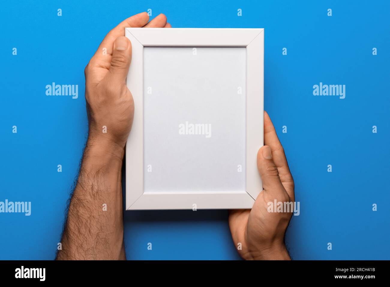 Man holding blank photo frame on blue background Stock Photo - Alamy