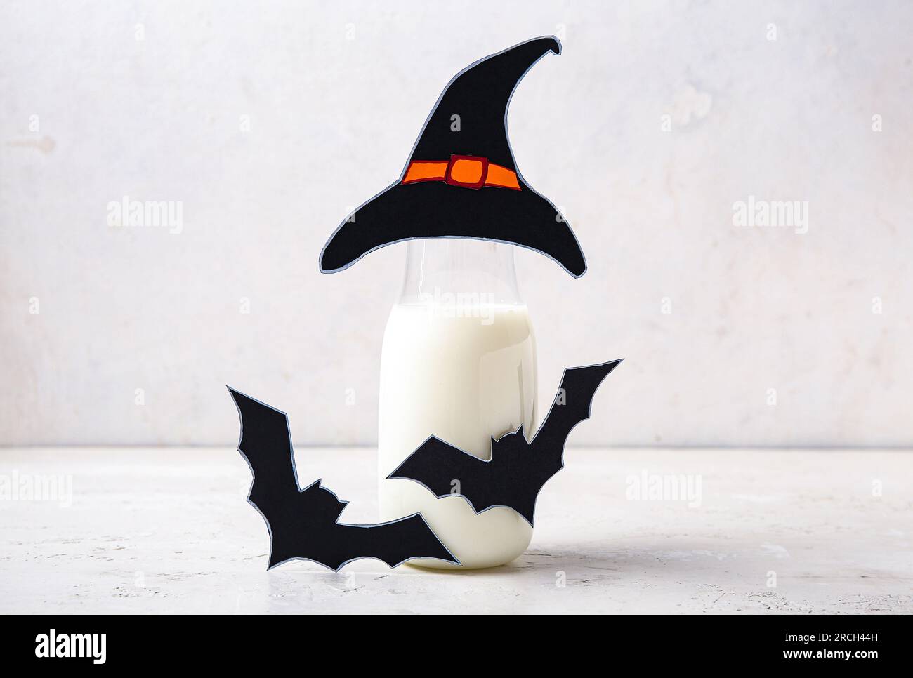 Bottle of milk, hat and bats made of paper for Halloween on light ...