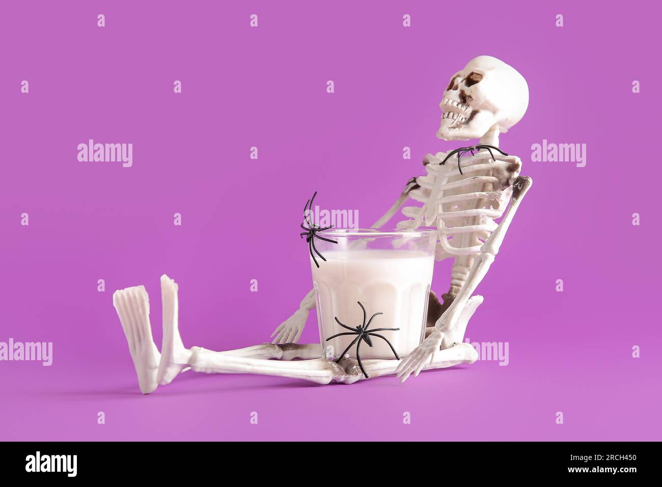 Glass of milk, spiders and skeleton for Halloween on purple background ...
