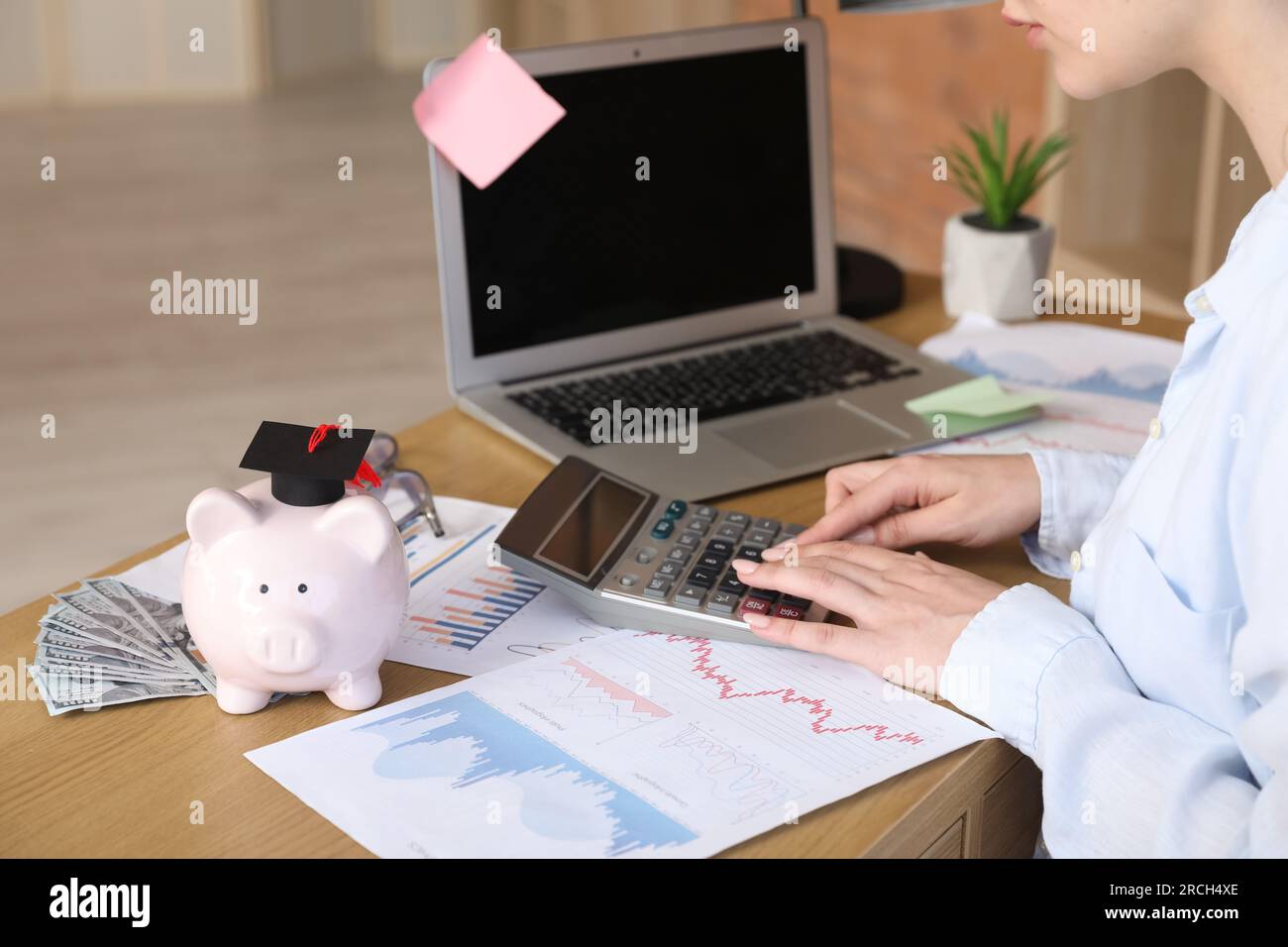 Female student calculating her finances with calculator and laptop at ...