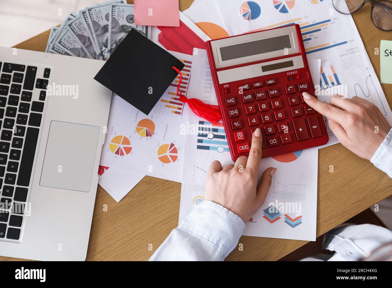 Female student calculating her finances with calculator and laptop at ...