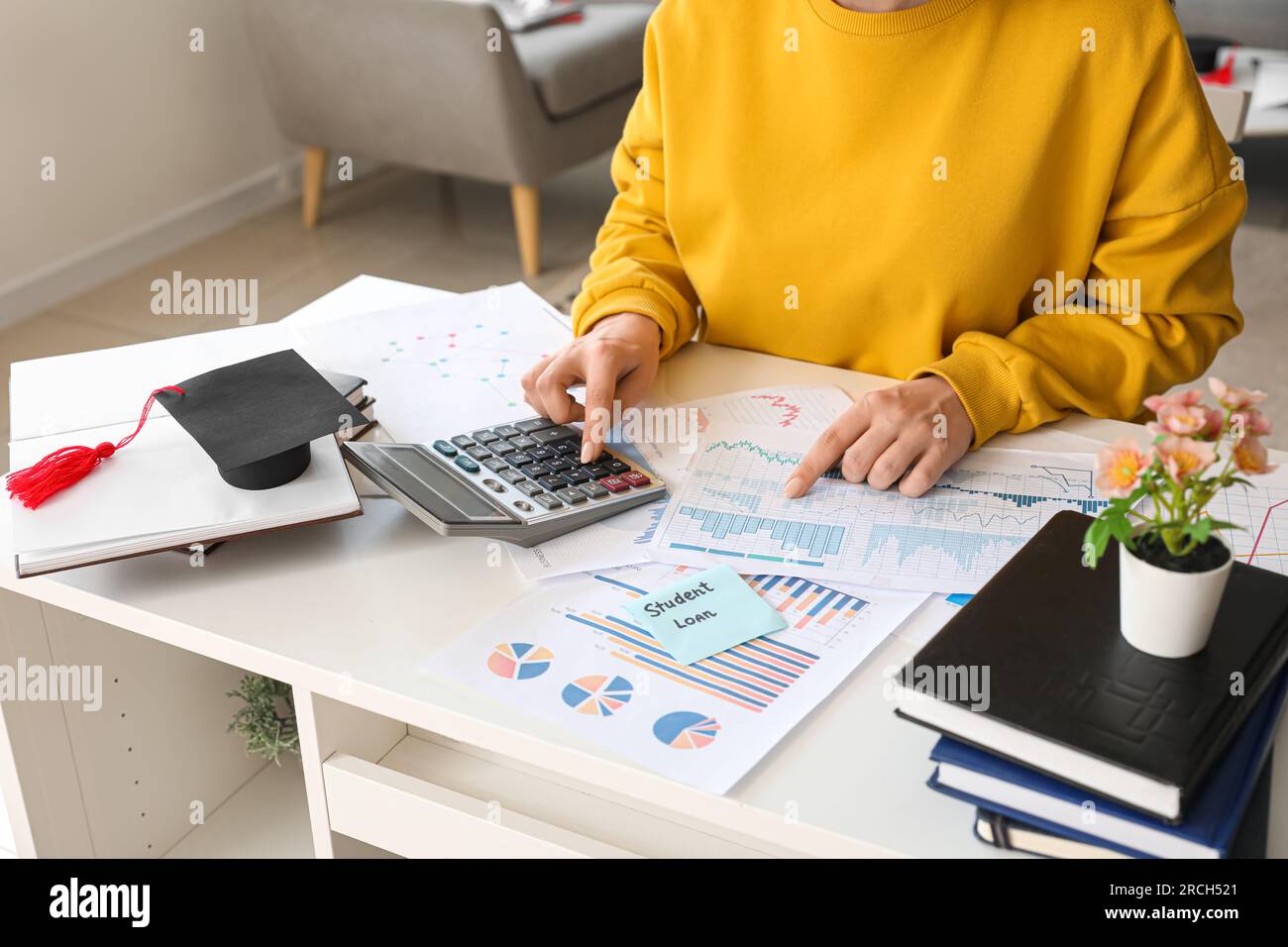 Female student calculating finances at table with graduation cap ...