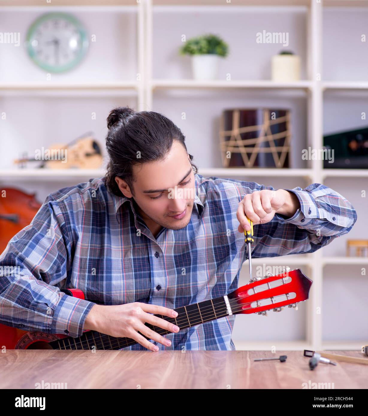 The young handsome repairman repairing guitar Stock Photo - Alamy
