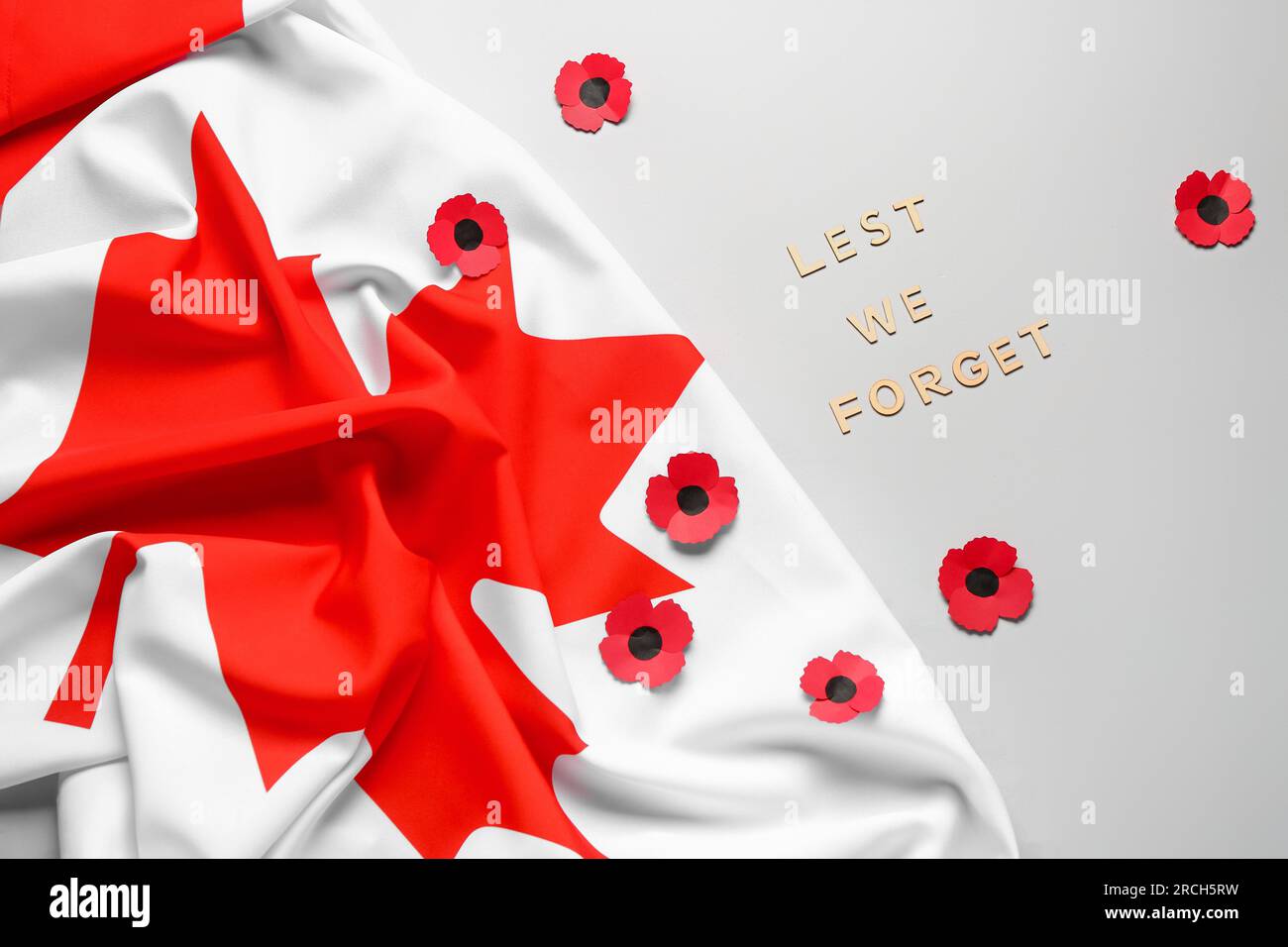 Poppy flowers with flag of Canada and text LEST WE FORGET on grey ...