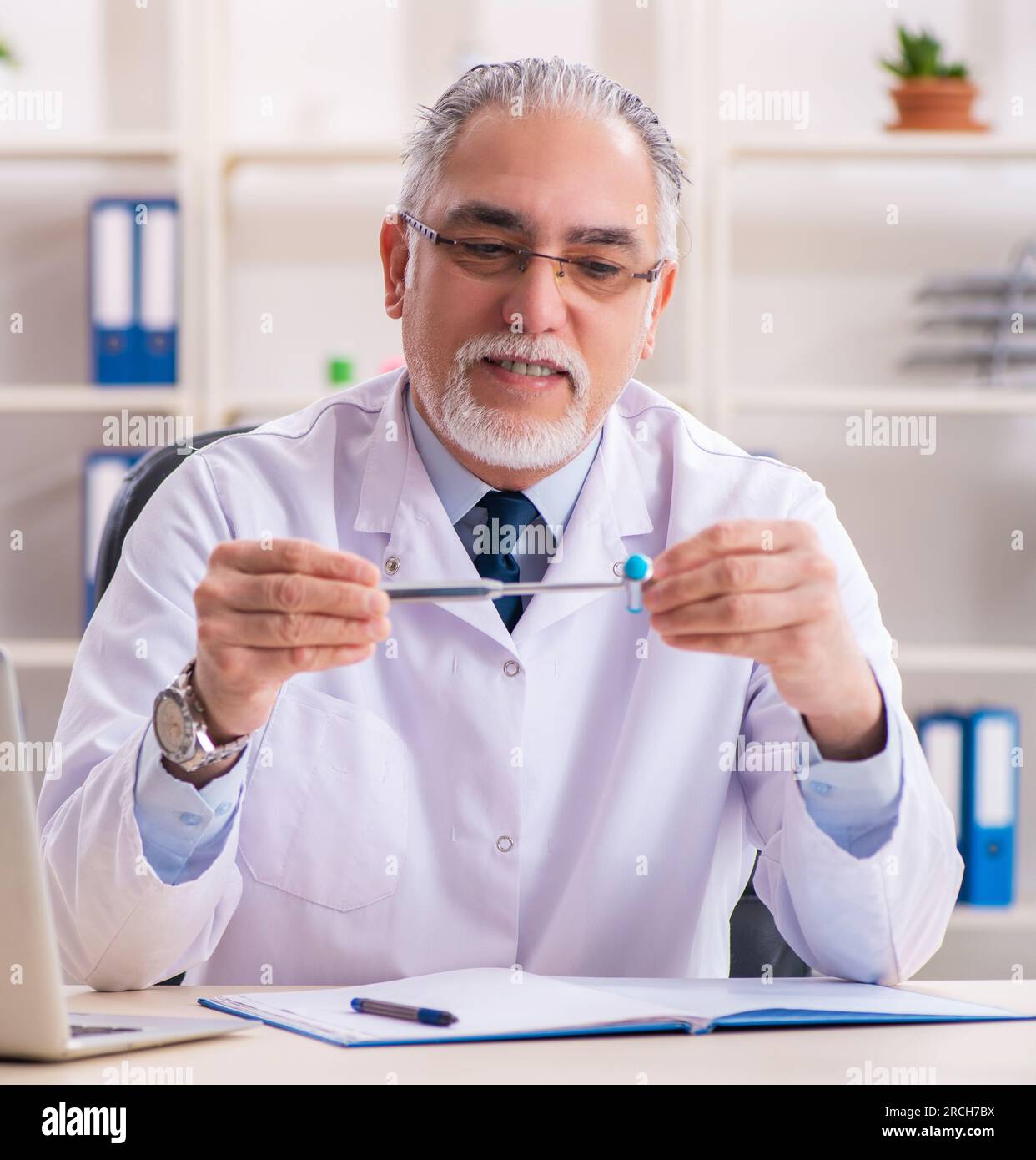 The aged male doctor with hammer Stock Photo - Alamy