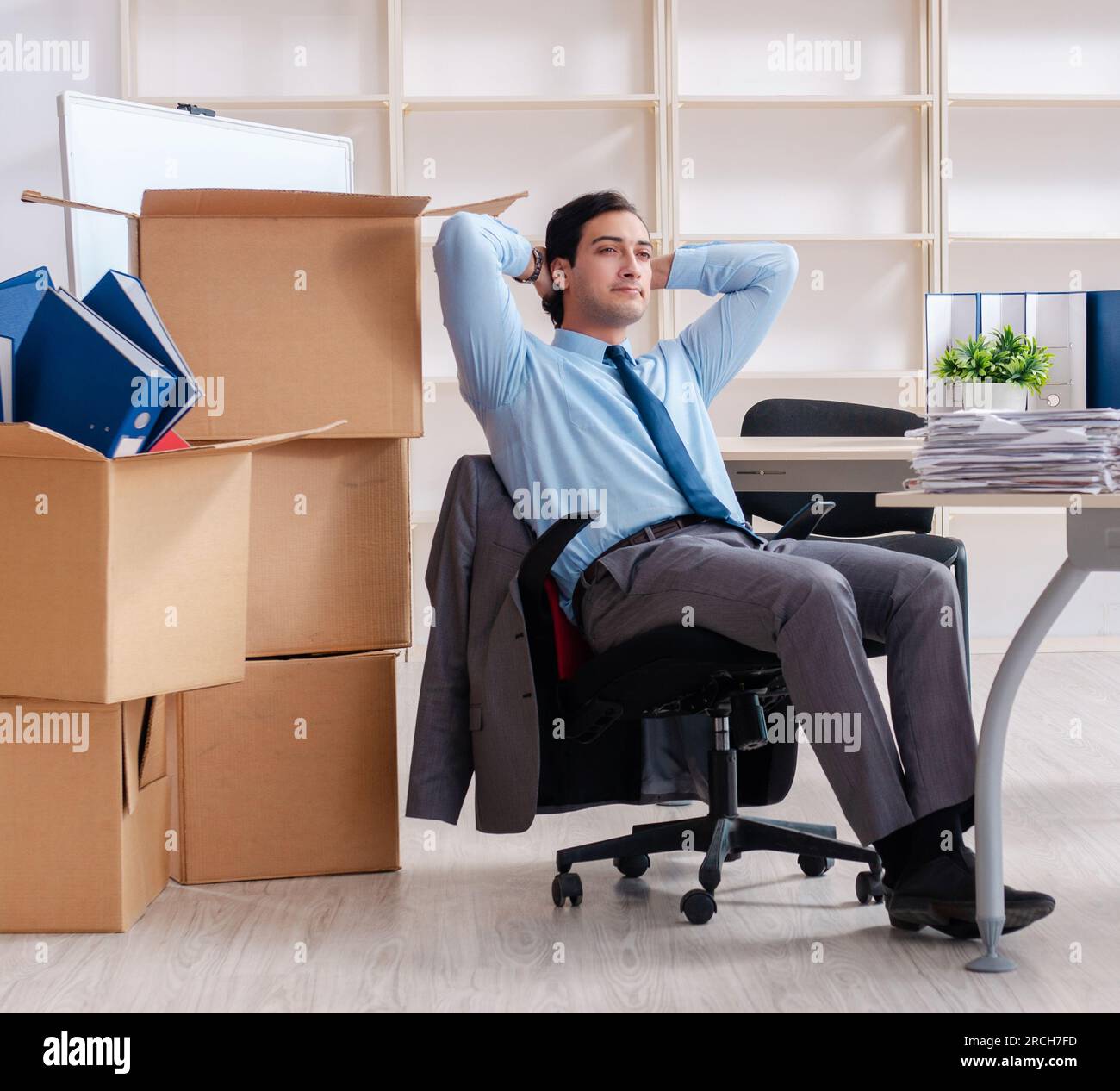 The young man employee with boxes in the office Stock Photo - Alamy