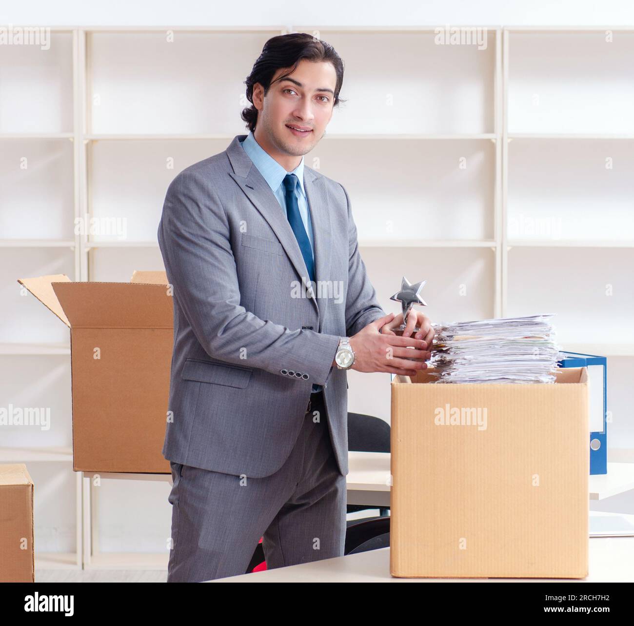 The young man employee with boxes in the office Stock Photo - Alamy