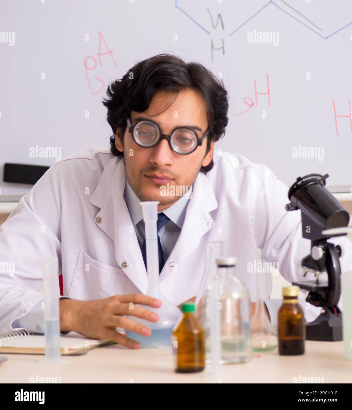 The young funny chemist in front of white board Stock Photo - Alamy