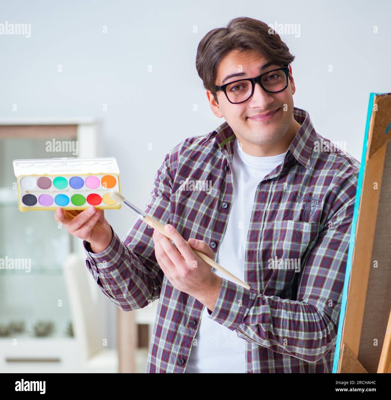 The young male artist drawing pictures in bright studio Stock Photo - Alamy