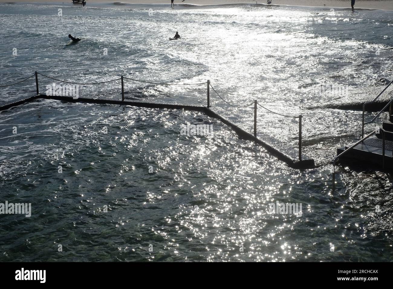 Afternoon sunlight on water, surfing at North Bondi, looking out across ...