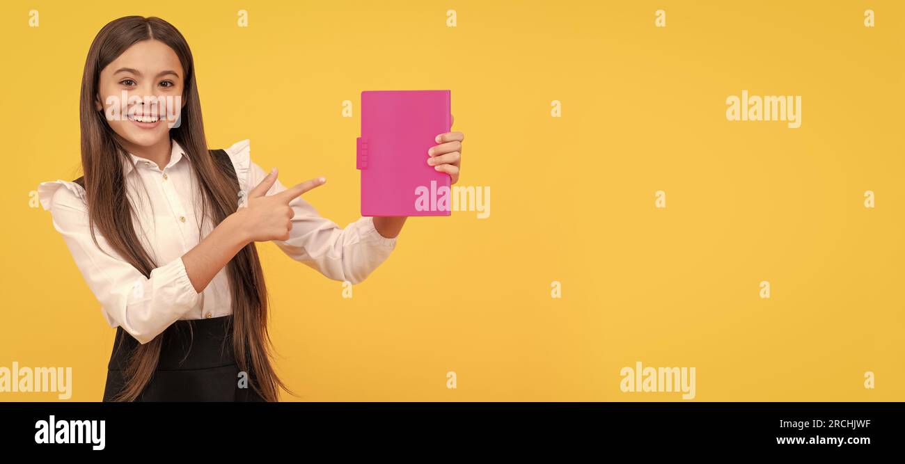happy teen girl in school uniform pointing finger on book, advertising ...