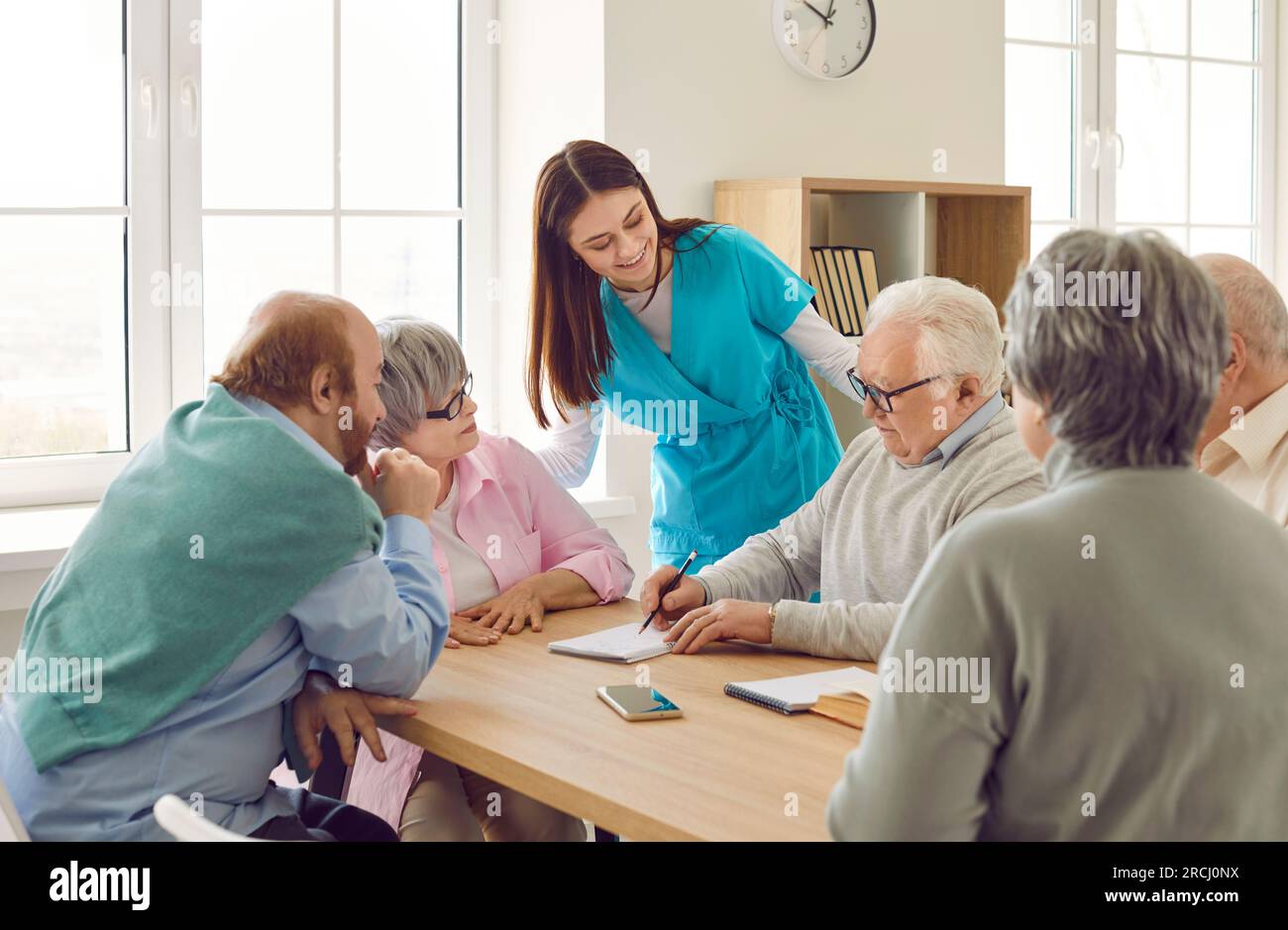 Young nurse woman having conversation with senior people sitting at the ...