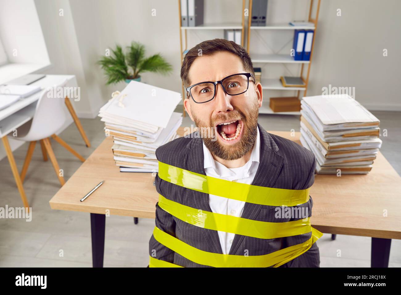 Angry stressed business man tied on his workplace in office shouting ...