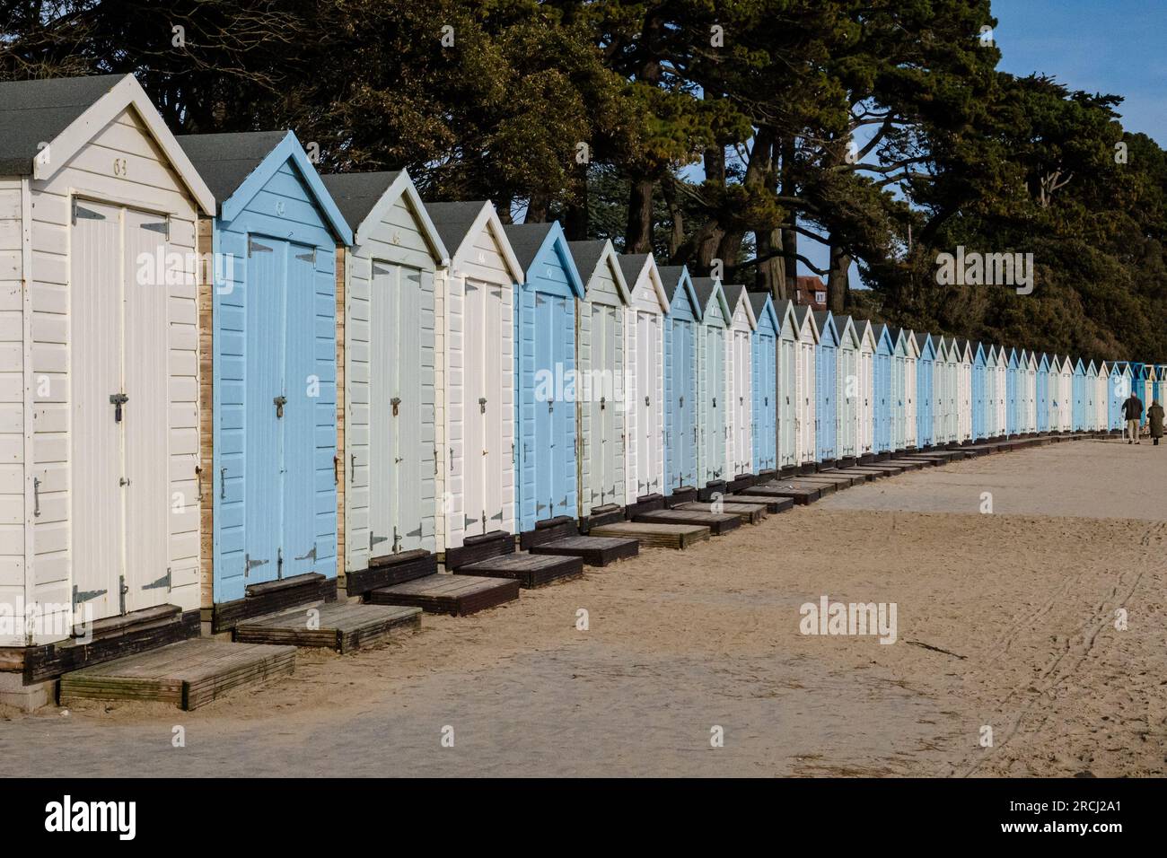 multi coloured pastel white blue grey beach huts in a line on the sea ...