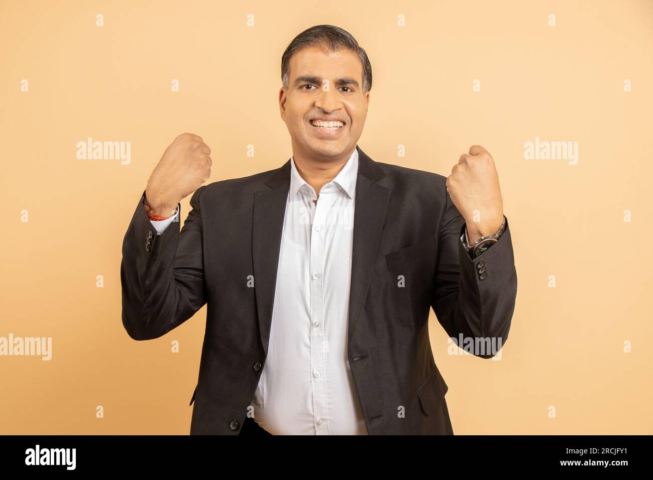 Excited mature indian man wearing black suit standing isolated over ...
