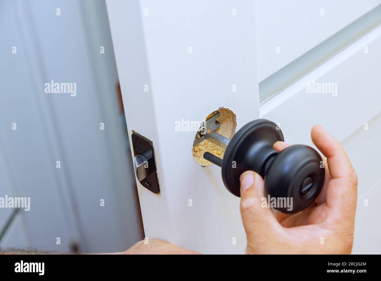 Worker successfully installs lock on new interior door Stock Photo - Alamy