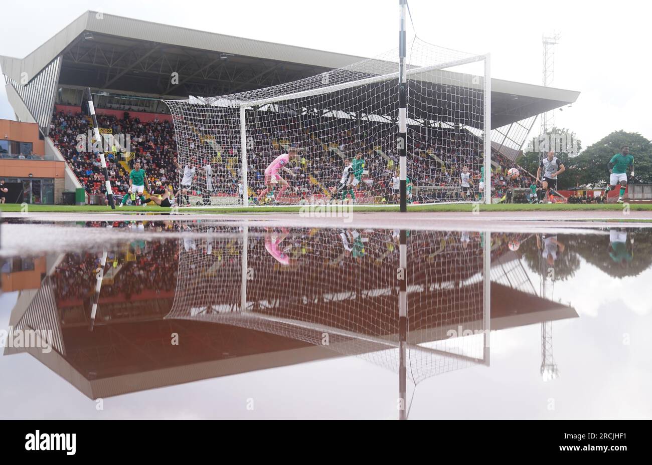 A general view of the game is reflected in a puddle on the sideline ...