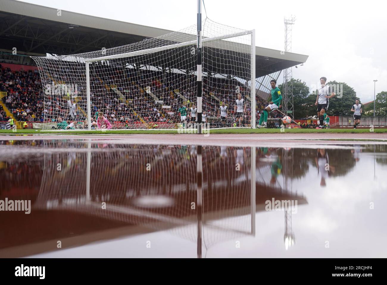A general view of the game is reflected in a puddle on the sideline ...