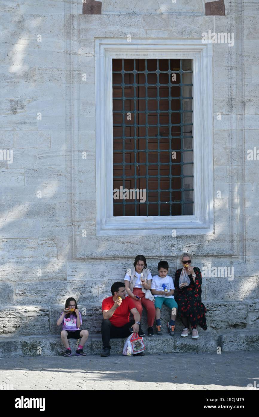 Turkish family sitting and eating outdoor next to an old wall in ...