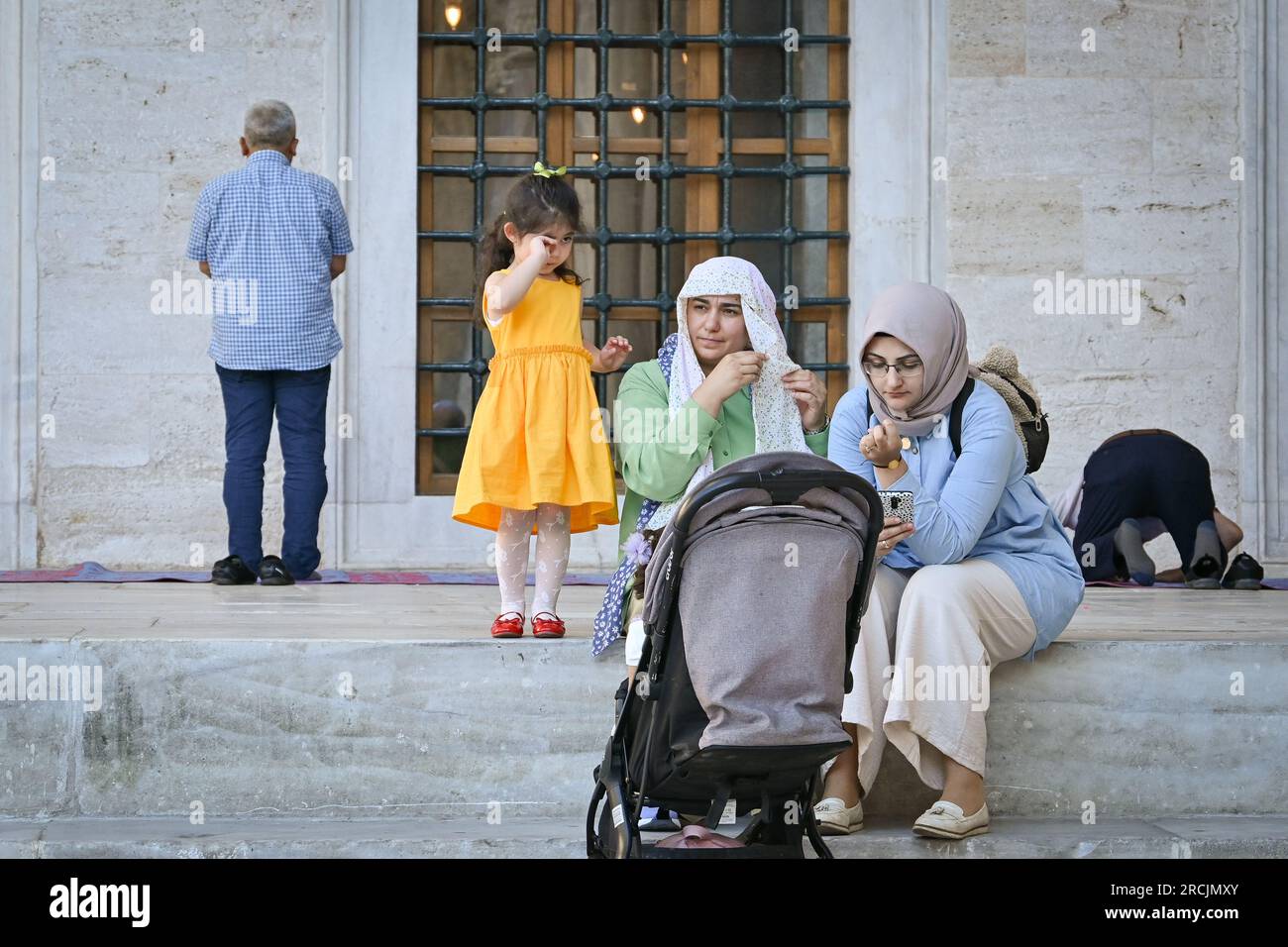 Turkish women with a child sitting on the steps of the Blue mosque in ...