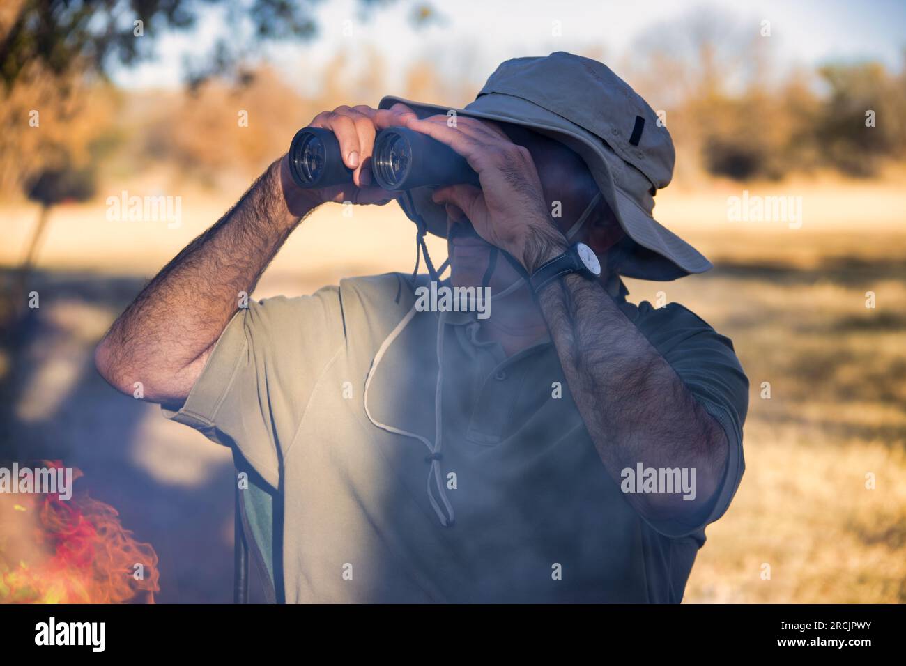 arab man with his binoculars and safari hat next to the camp fire ...