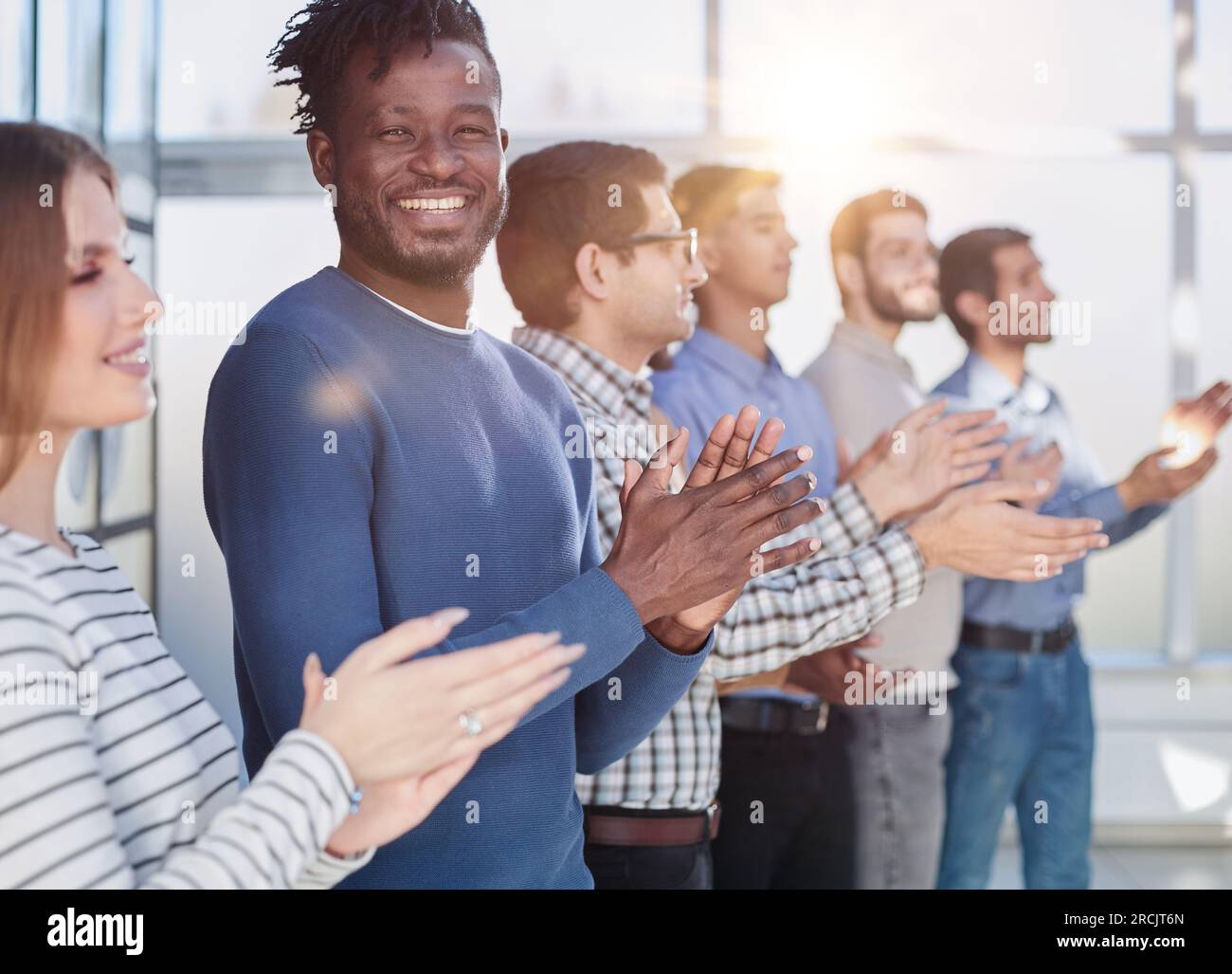 Diverse group of business people smiling and clapping with a standing ...