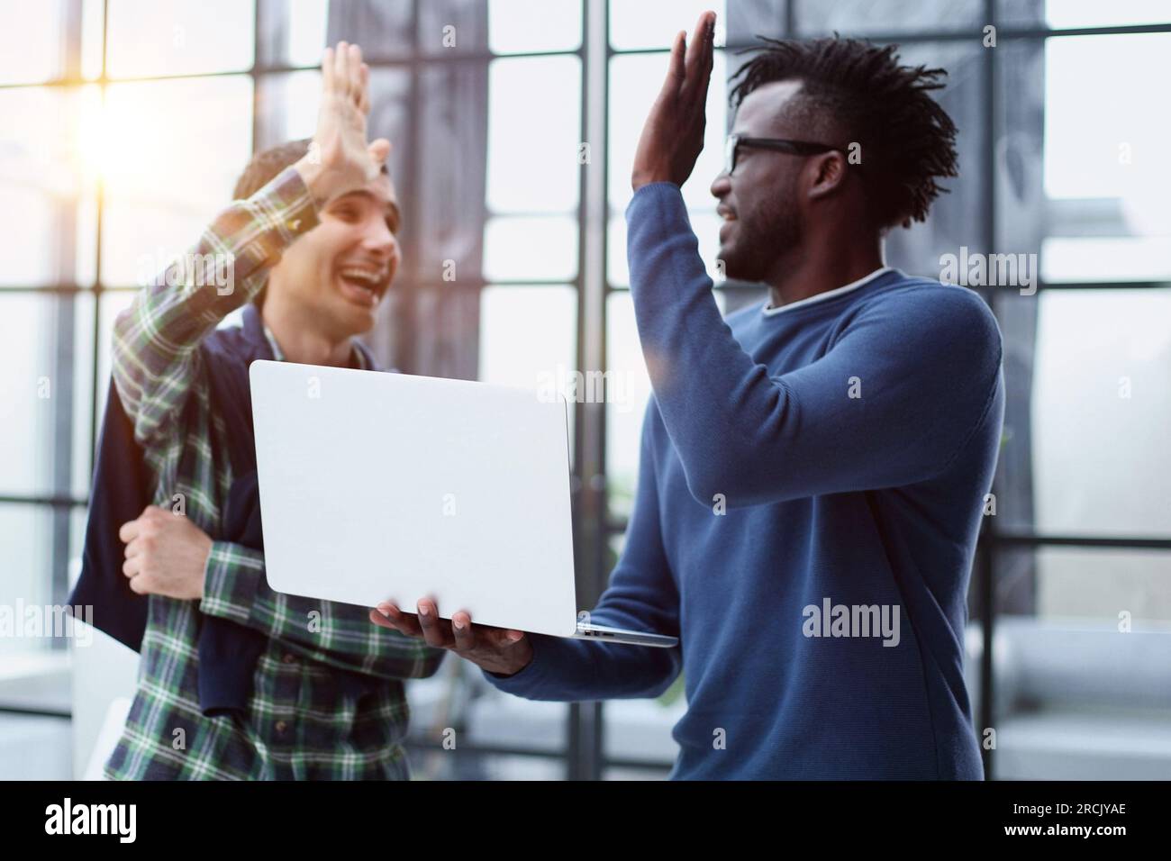 Happy multicultural programmers giving high five while working in ...