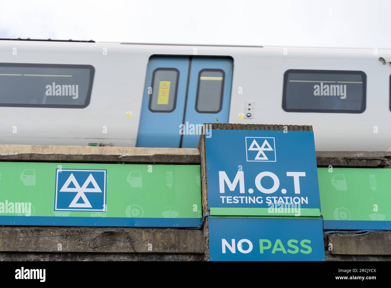 Thameslink train travels past over a bridge with ads for MOT test ...