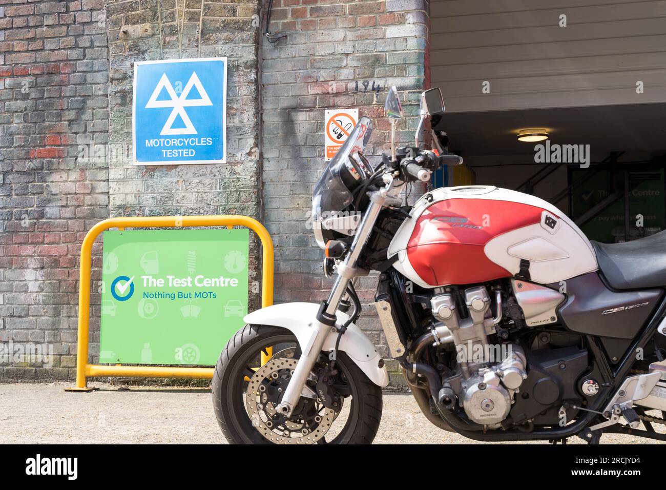 A motorcycle parks outside a MOT test bay with MOT logo attached to its ...