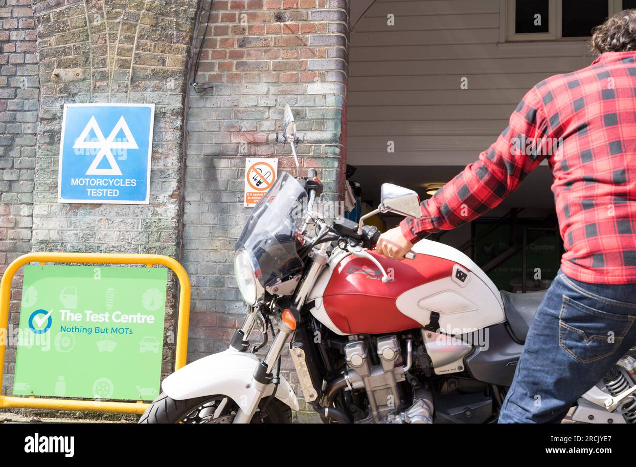 A man arrives at MOT test centre to have Motorbike to MOT tested ...