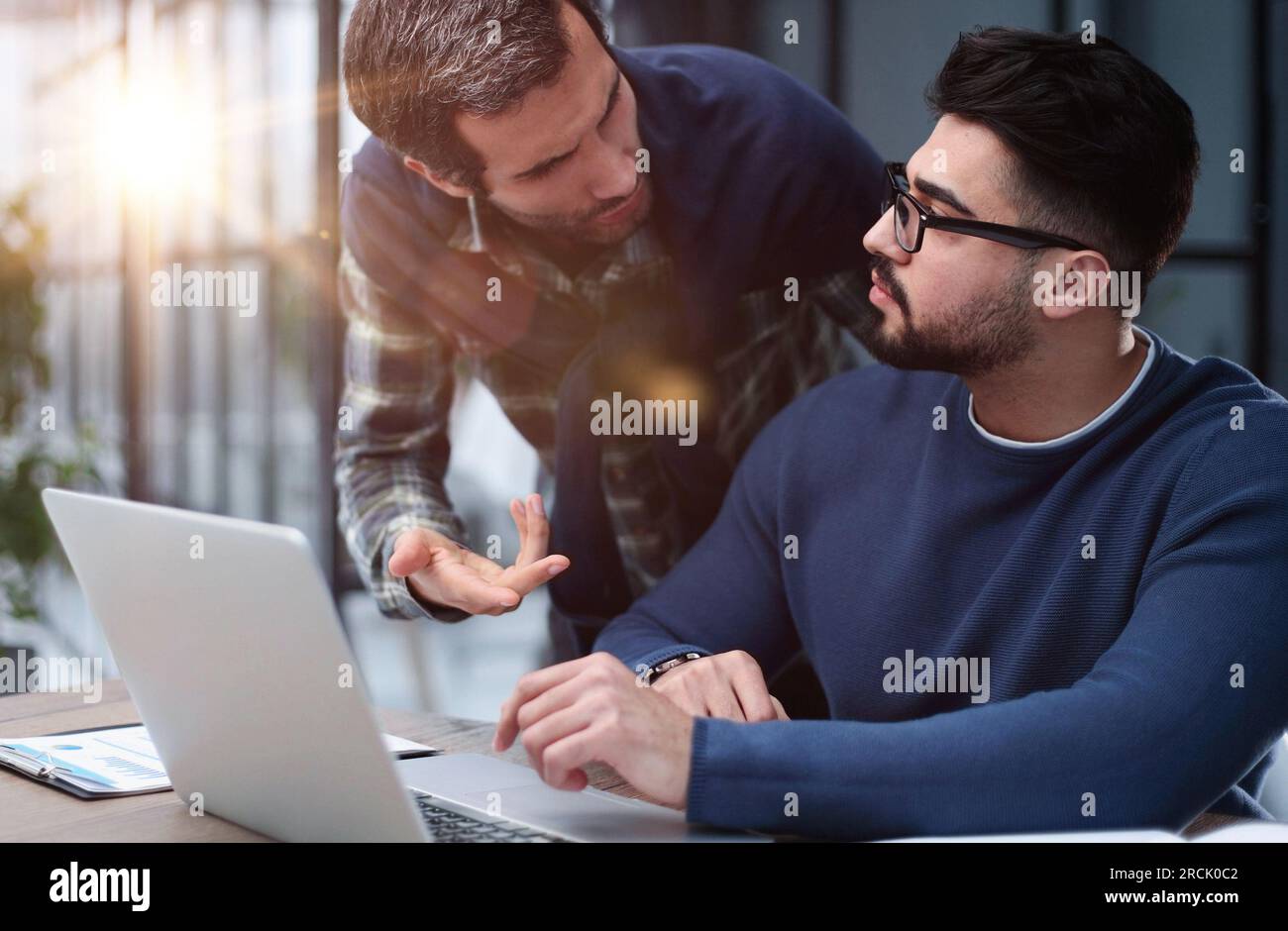 two male colleagues are talking at the table in the office Stock Photo ...