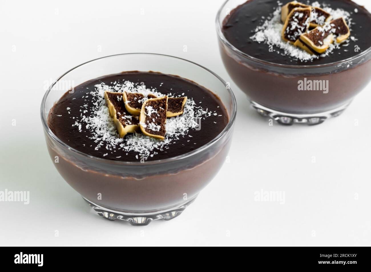 Cocoa pudding, coconut decorated,in glass bowls,on white surface Stock ...