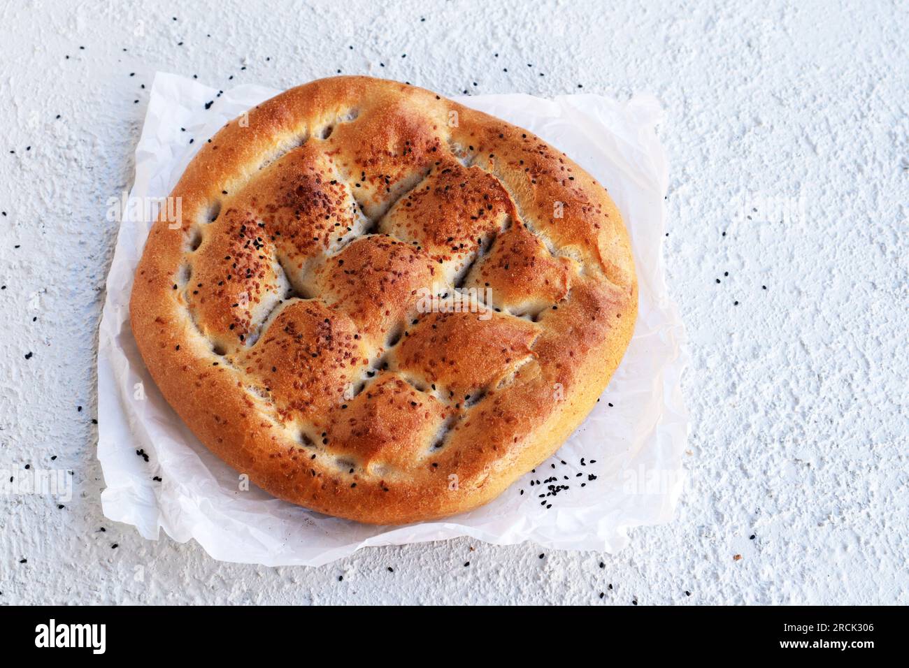 Traditional Turkish Ramadan Bread with baking paper on white textured ...