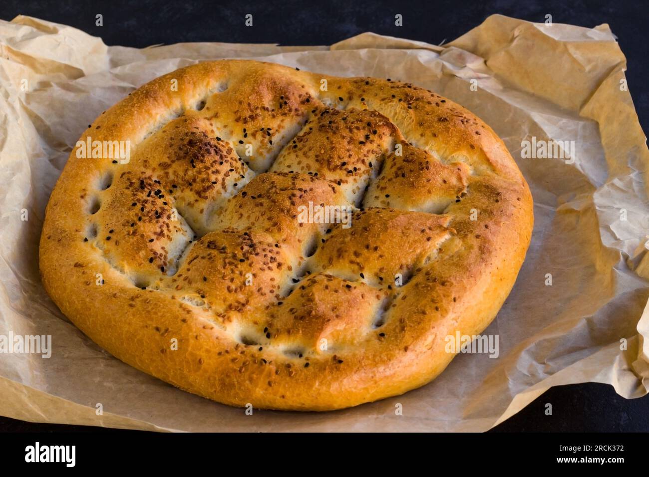 Traditional Turkish Ramadan Bread with oven baking paper on black ...