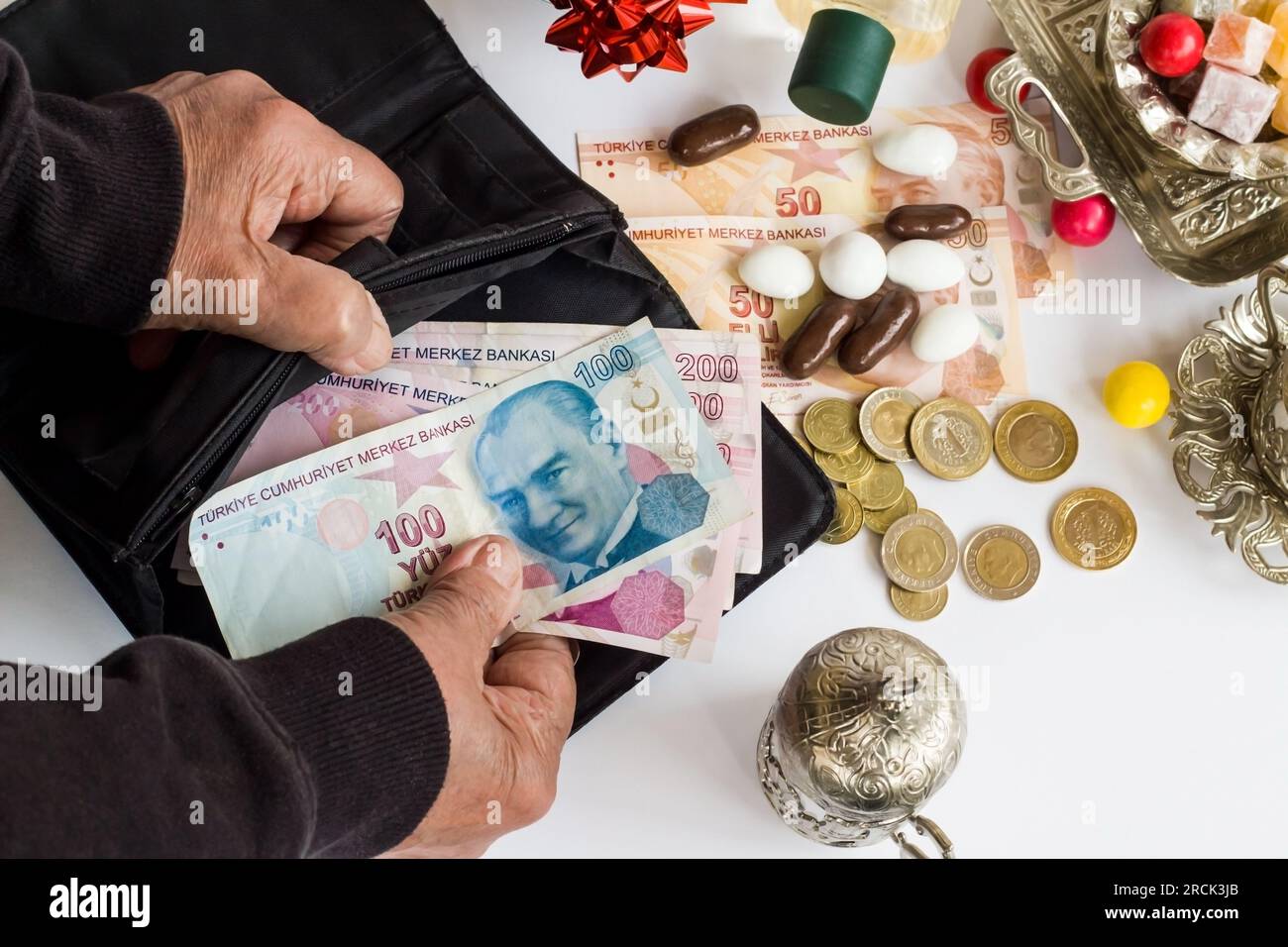 Old hand takes Turkish lira out of black wallet on white surface with ...