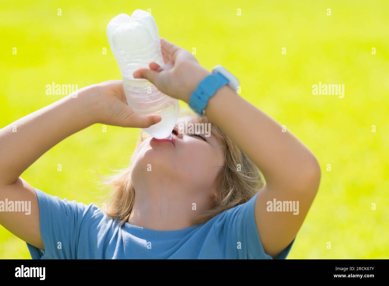 Kid drinking a fresh glass of water. Thirsty kid holding glass drinks ...