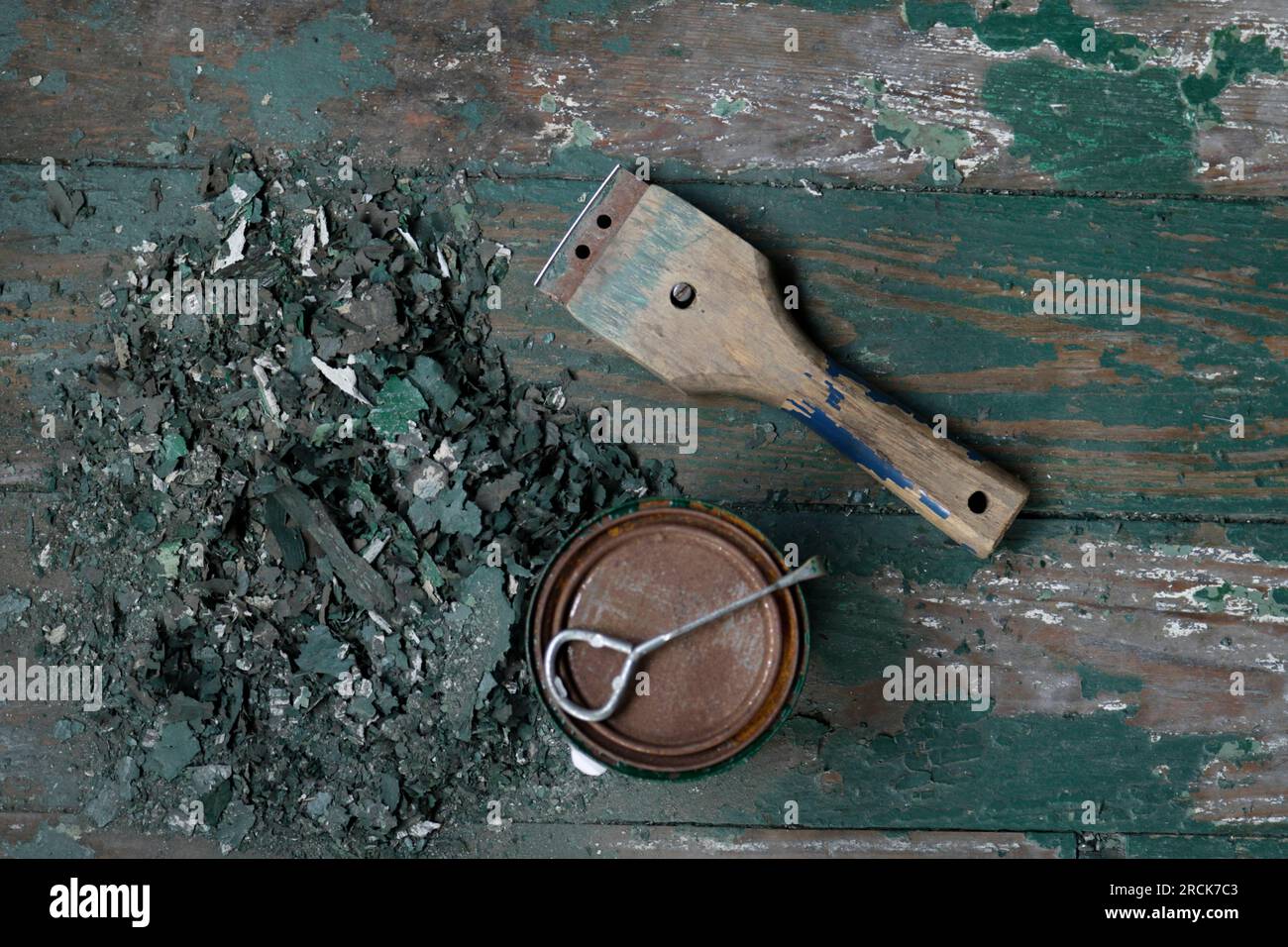 Scraping old peeling paint with a hand scraper from a wide plank wood ...