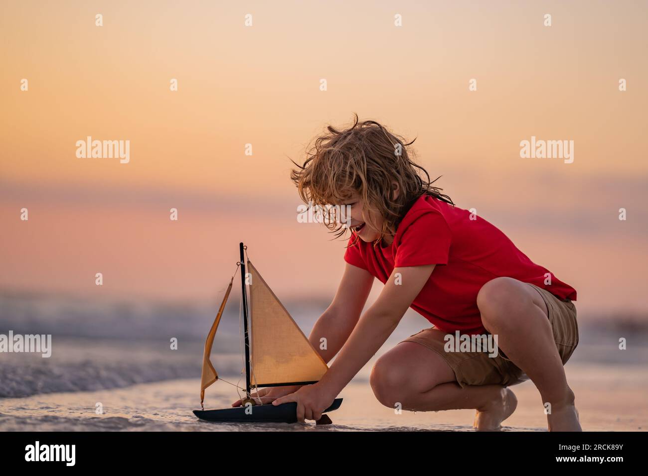 Child playing with a toy boat. Little kid boy sailing toy ship on sea ...