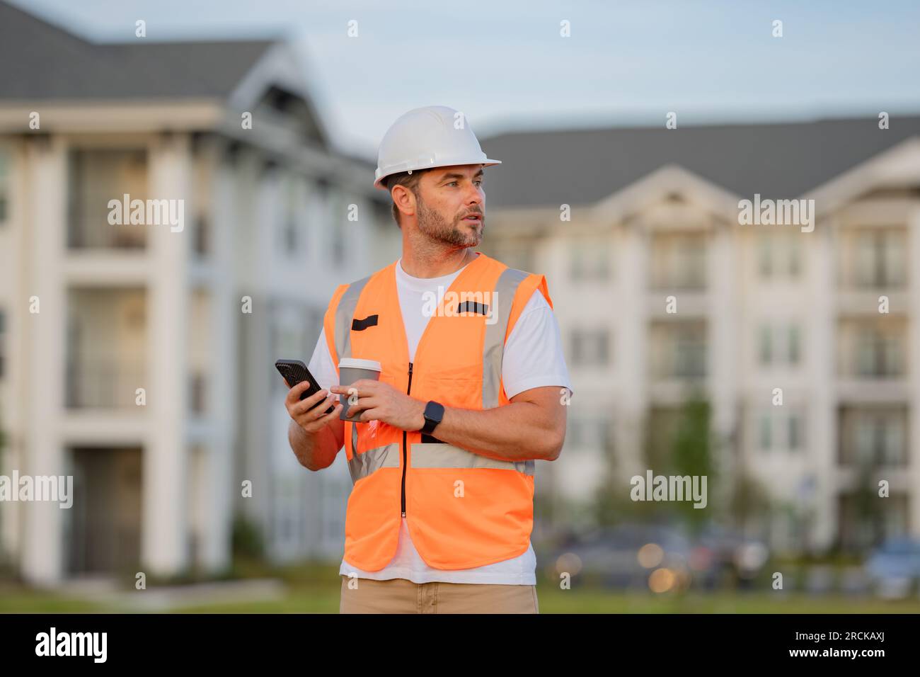 Engineer builder drinking take away coffee using phone on break ...